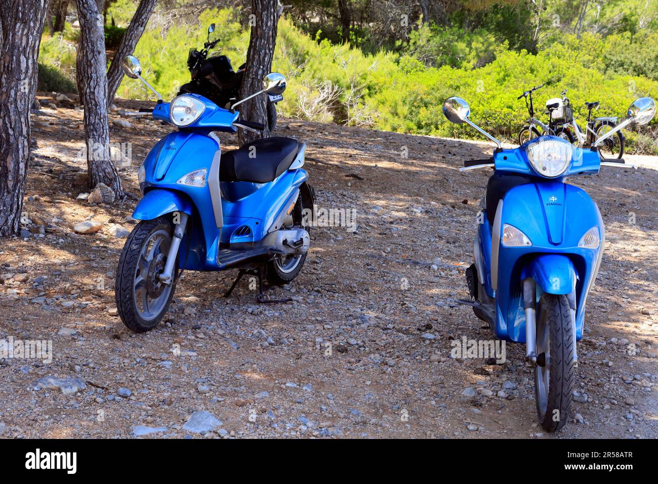 Two matching metallic blue scooters parked at Dragonera beach, Agistri ...