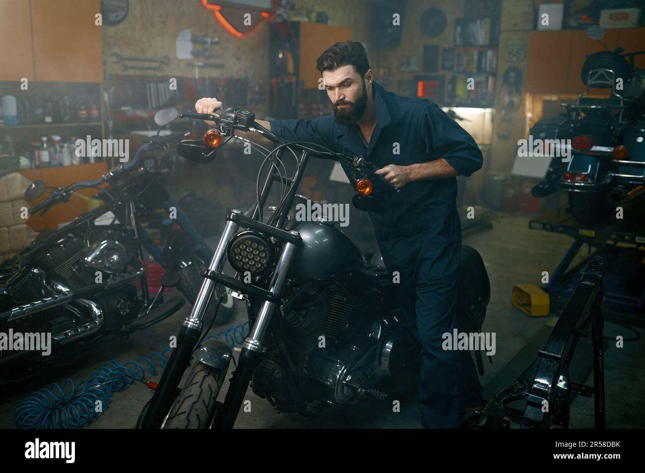 Auto mechanic pushing motorcycle on repair stand in workshop garage ...