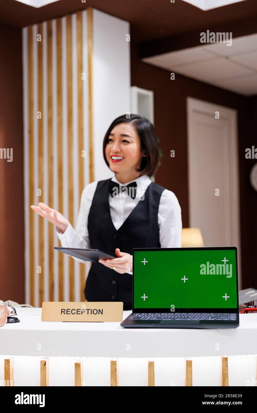 Hotel worker with green screen on desk, welcoming people and working on ...