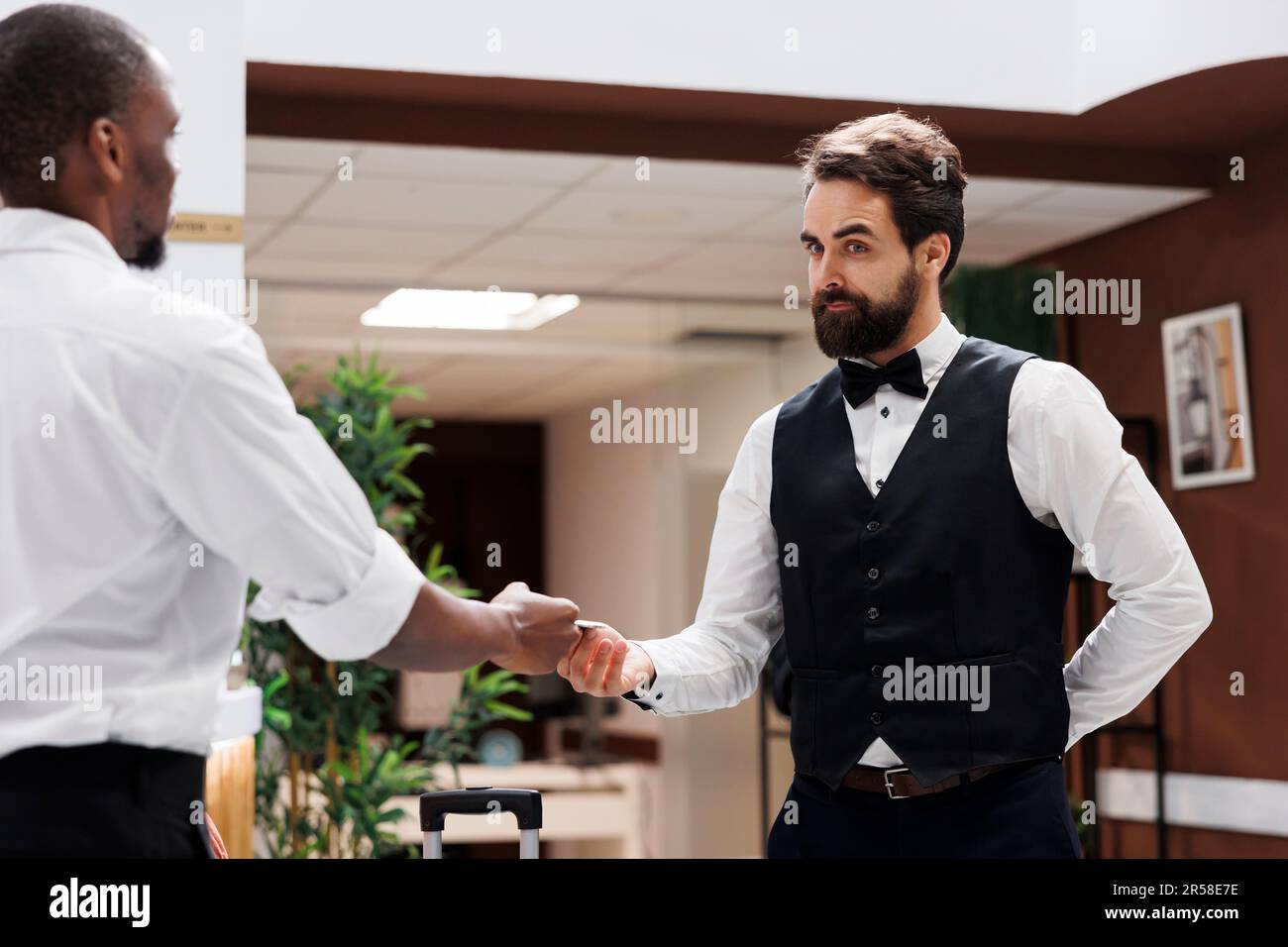 Steward taking cash money from guest at reception counter, offering ...