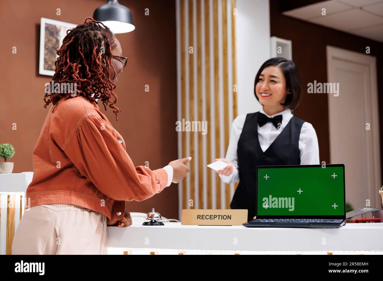 Woman giving room key card to tourist, using laptop with isolated ...