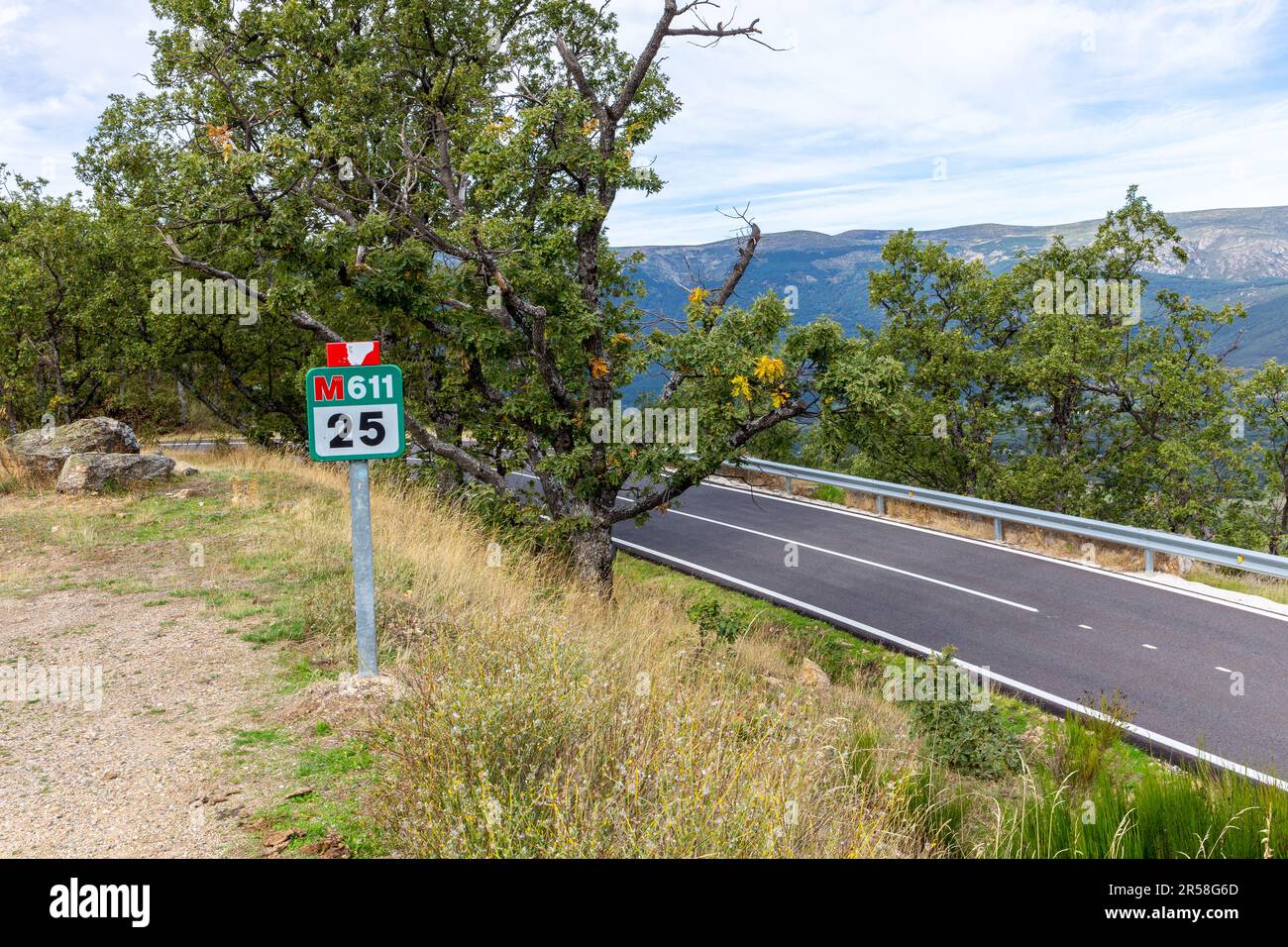 Tarmac road with M-611 road number sign and oak trees in Cuenca Alta ...