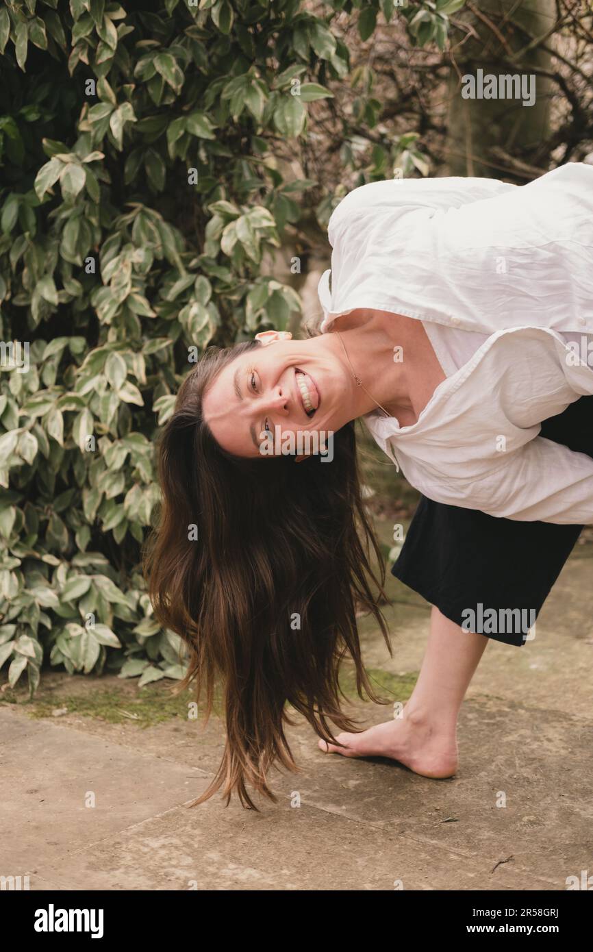 Happy smiley female yoga teacher in bound extended side angle in leafy ...