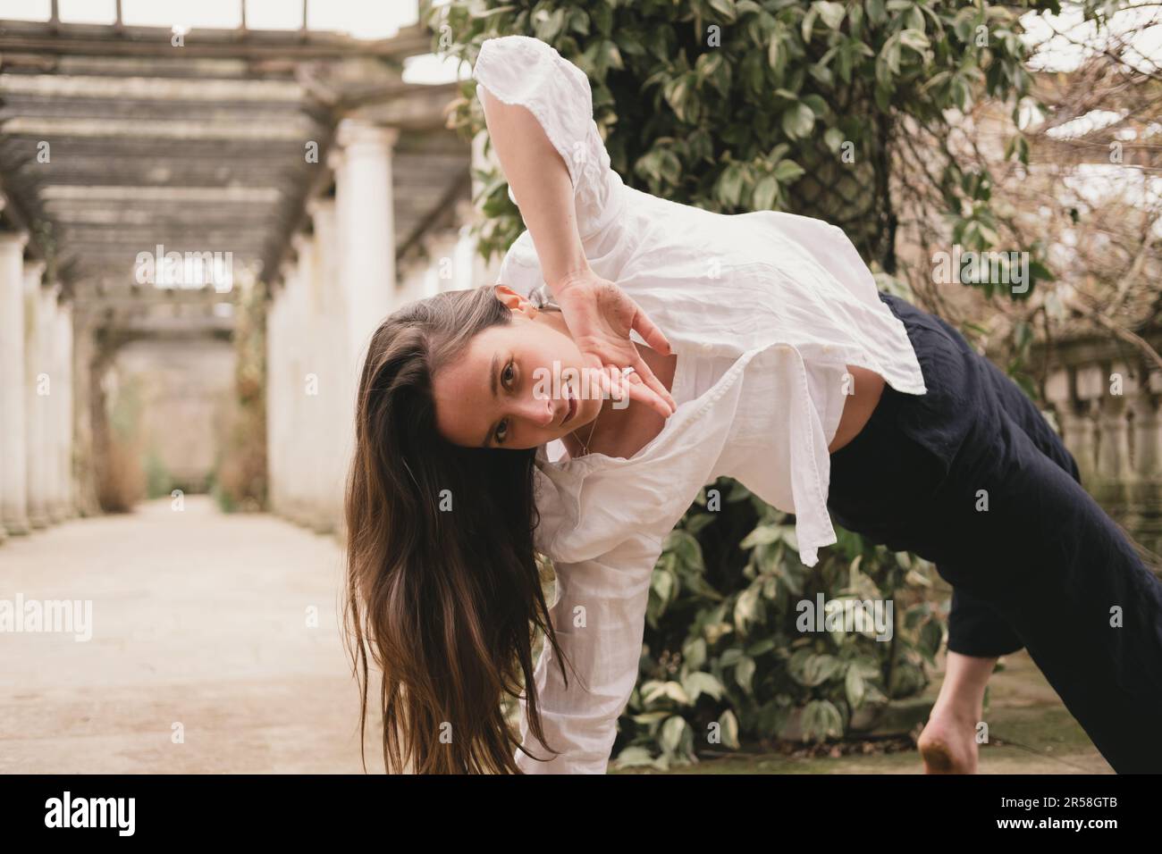 Smiley woman yogi in wild thing pose in a dreamlike leafy terrace of a ...