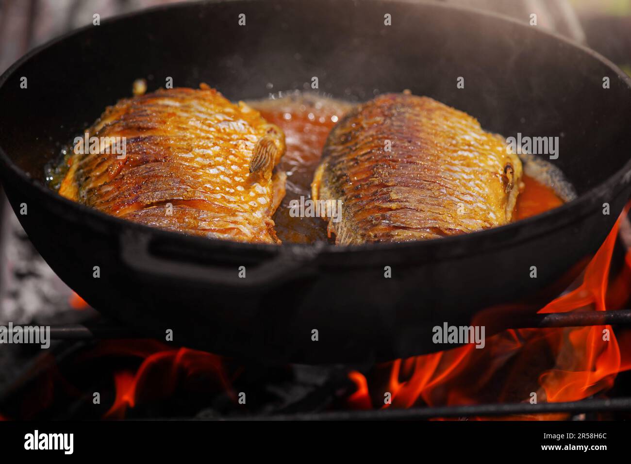 The fish is fried in a pan in oil on a fire. Cooking fish Stock Photo ...