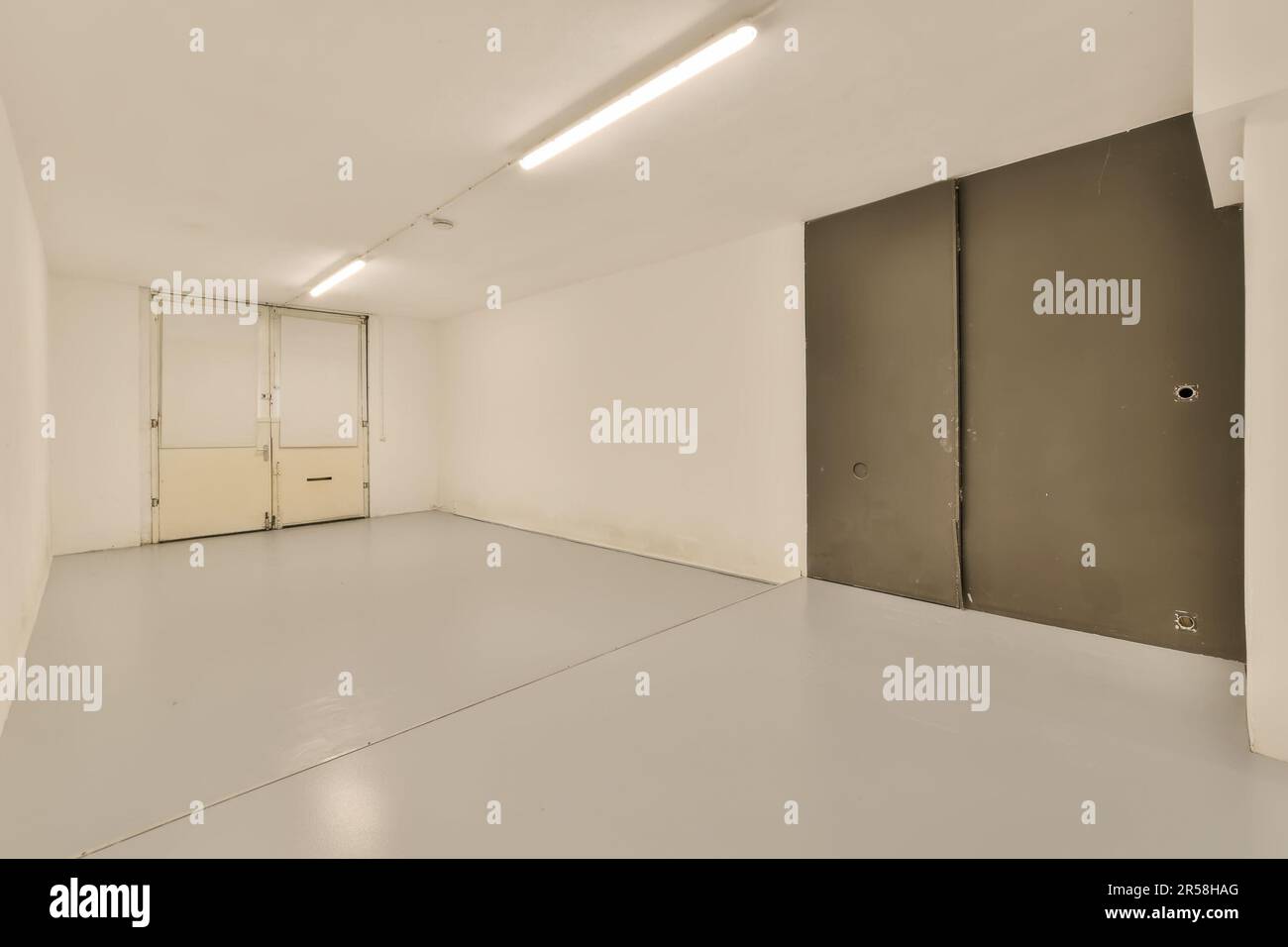 an empty room with white walls and flooring, there is a black door in ...