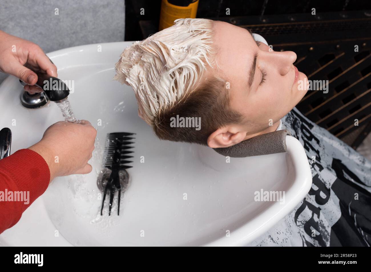Young handsome guy of European appearance in the process of washing off ...