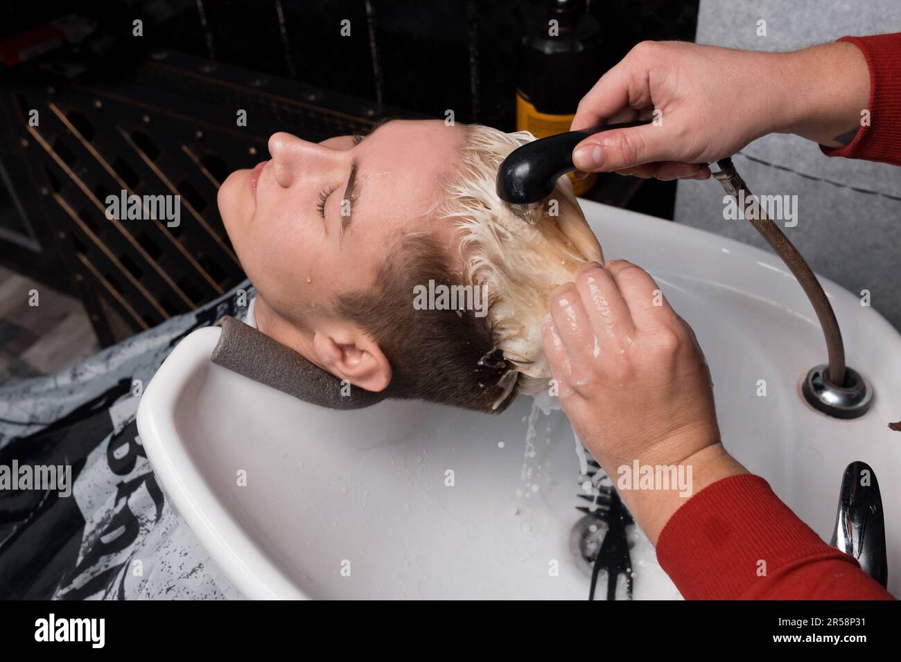 A professional barber washes the white dye from a young guy's client's ...