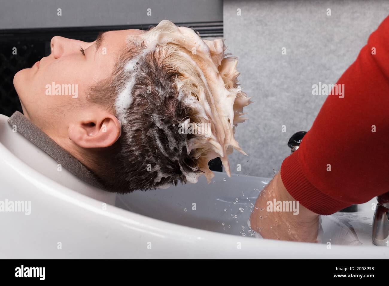 The client is a young European guy in the process of washing his hair ...