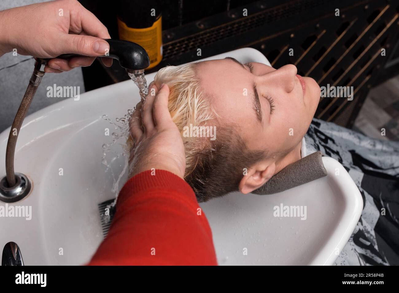 The hands of a barbershop worker, hairdresser wash the hair of a client ...