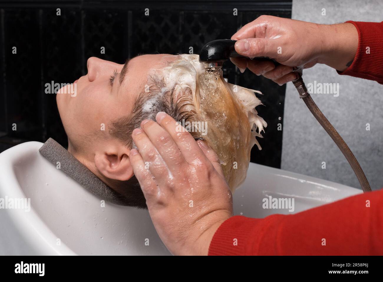 The barber's hands wash the hair and head of the guy's client with rain ...
