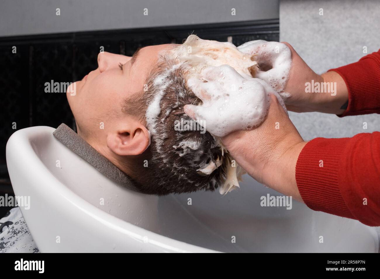 Hairdresser's hands wash the head and hair of a young guy's client with ...