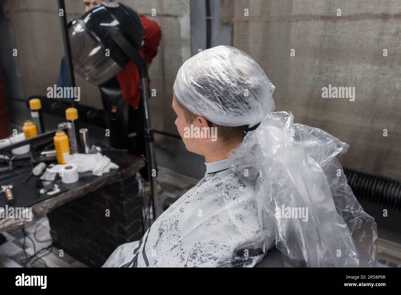 The process of dyeing hair in a barbershop, the guy's head is wrapped ...
