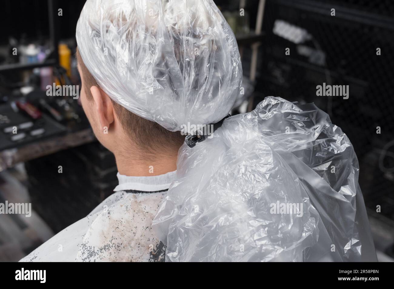 Barbershop client man's head close-up in plastic film professional hair ...