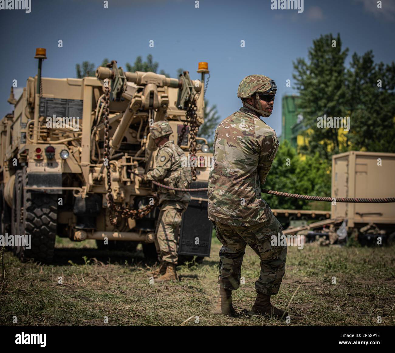U.S. troops connect towing cables between two tactical vehicles during ...