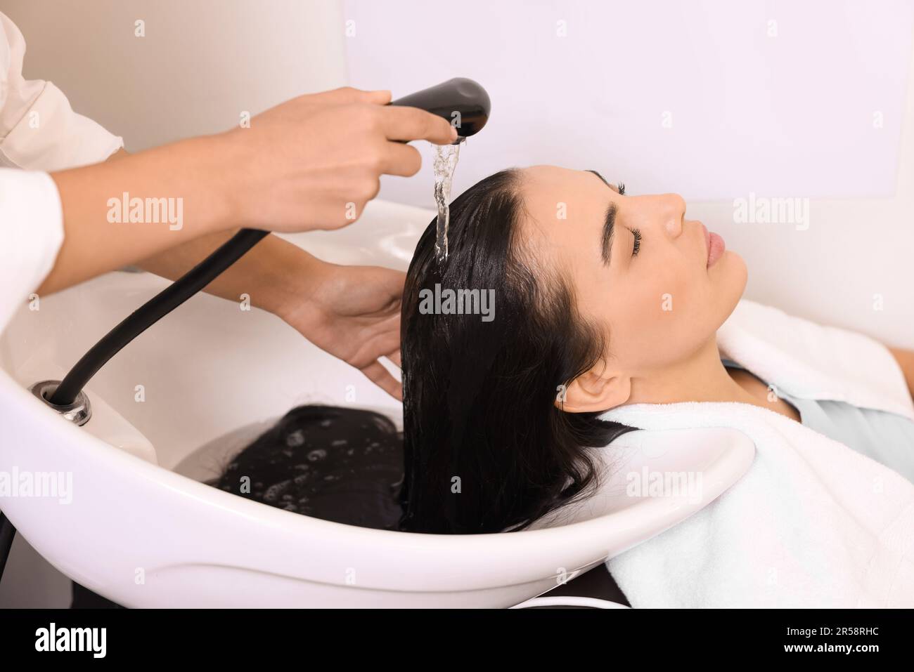Professional hairdresser washing woman's hair in beauty salon, closeup ...