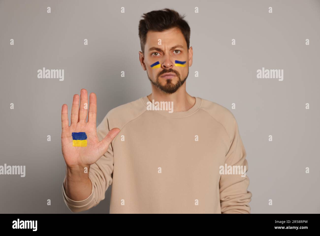 Angry man with drawings of Ukrainian flag against light grey background ...