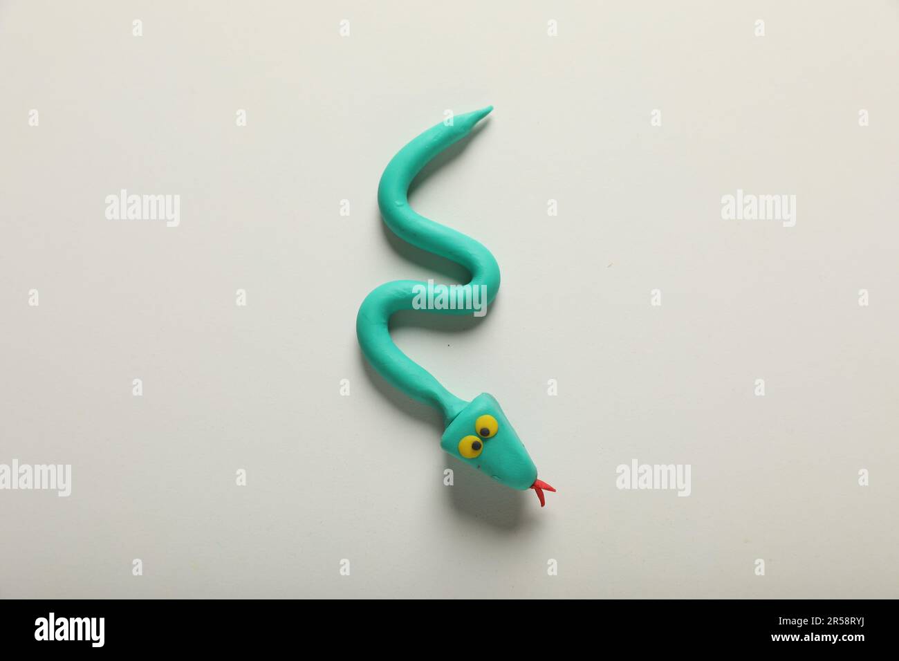 Turquoise plasticine snake isolated on white, top view Stock Photo - Alamy