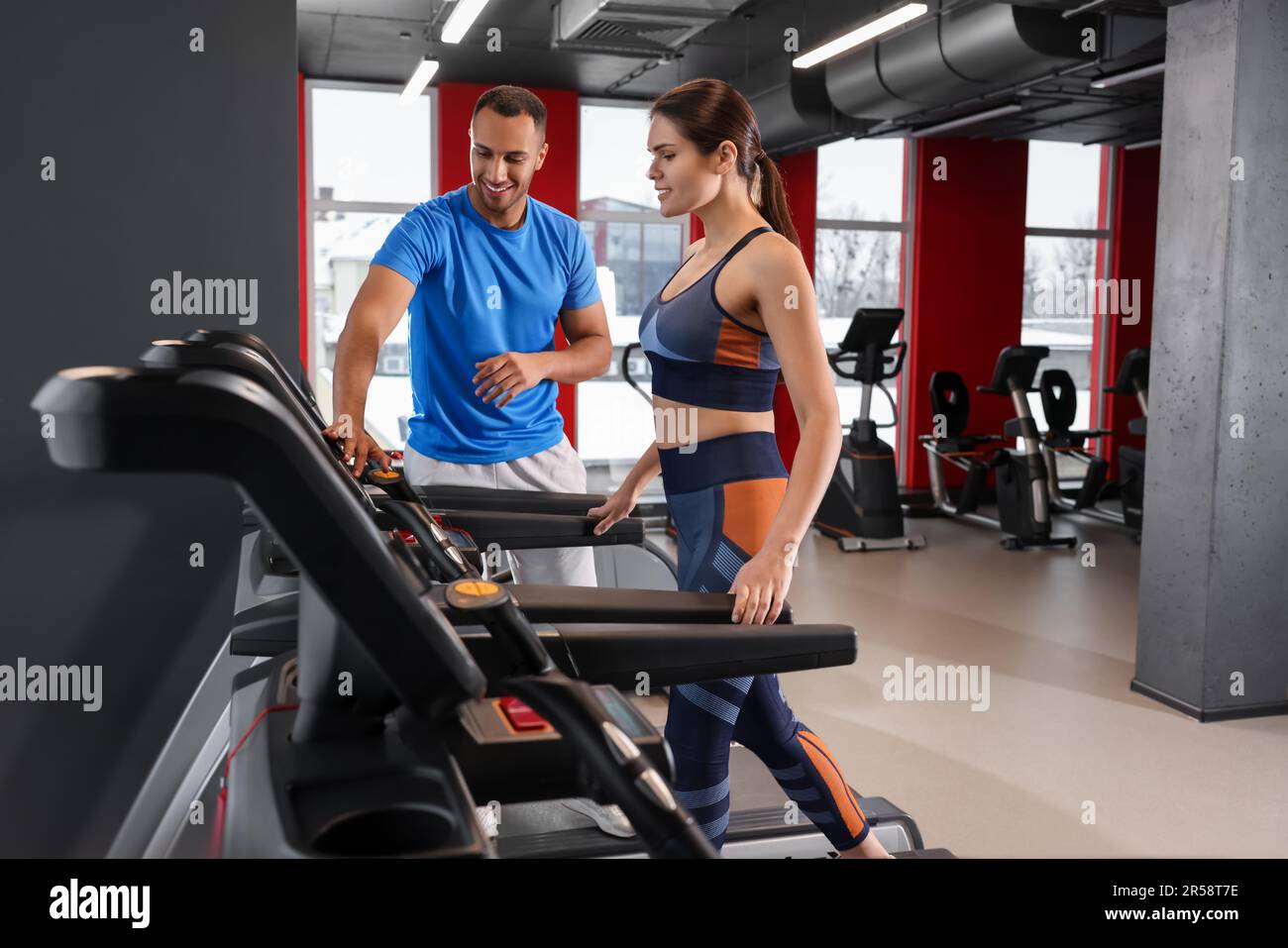 Happy trainer explaining woman how to do exercise properly in modern ...