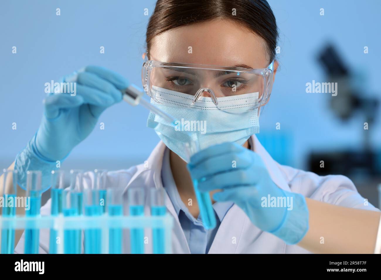 Scientist dripping liquid from pipette into test tube in laboratory ...