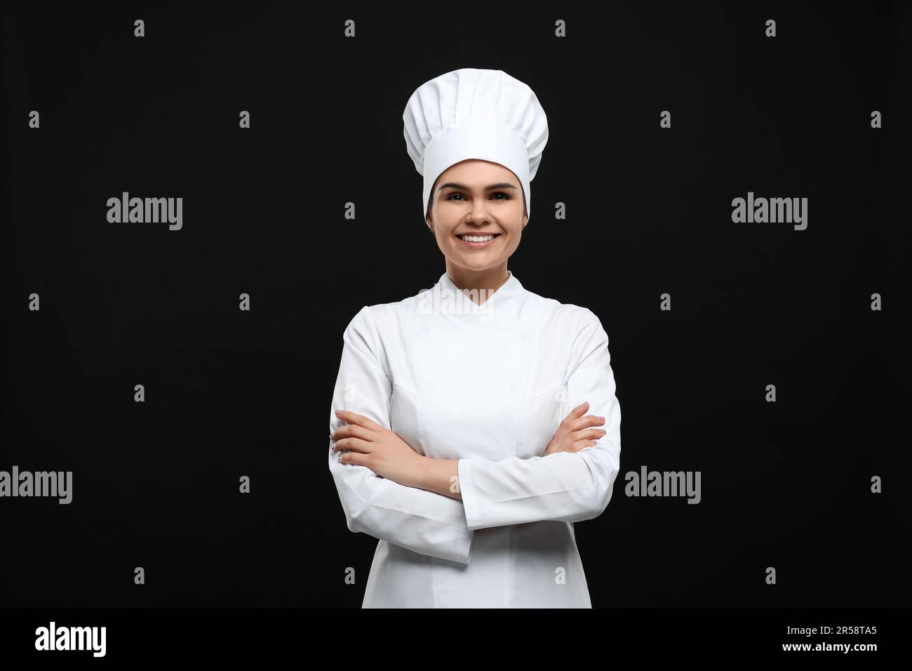 Happy female chef wearing uniform and cap on black background Stock ...