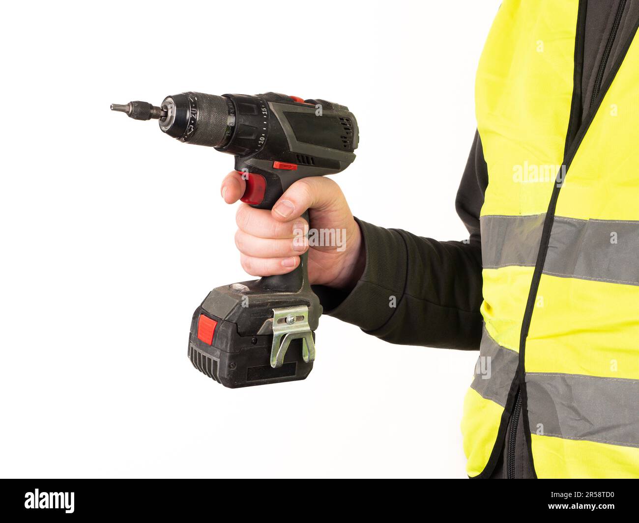 A worker in a safety vest holds a cordless screwdriver in his hand. No ...