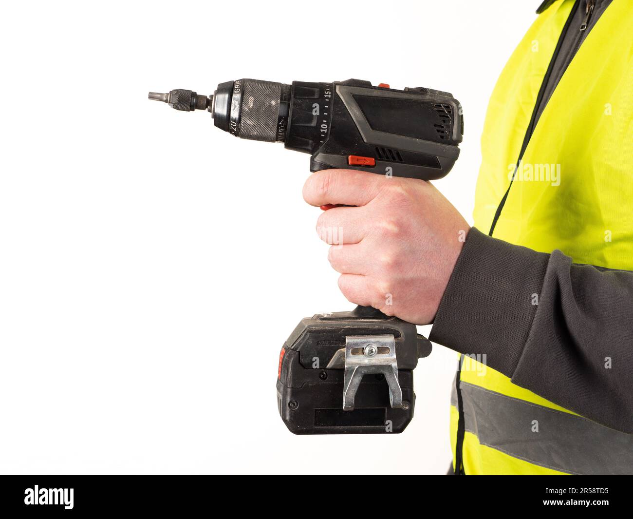 A worker in a safety vest holds a cordless screwdriver in his hand. No ...