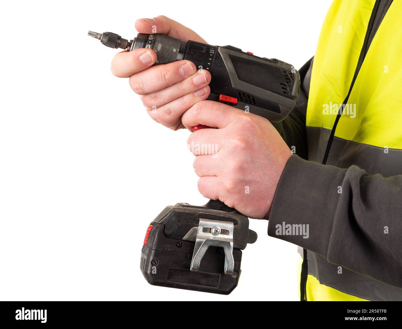 A worker in a safety vest holds a cordless screwdriver in his hand. No ...