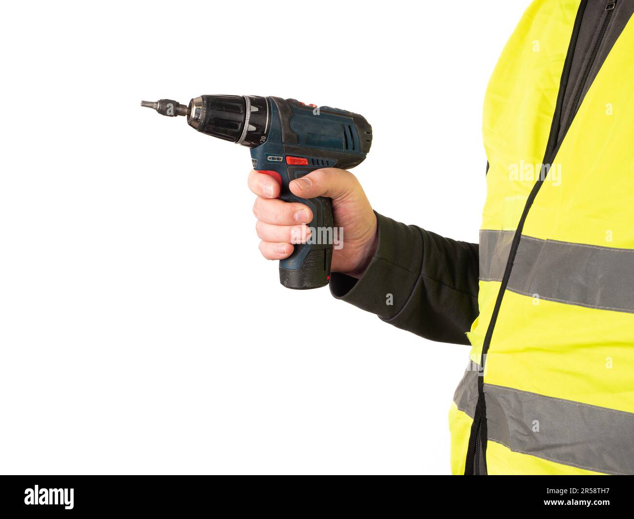 A worker in a safety vest holds a cordless screwdriver in his hand. No ...