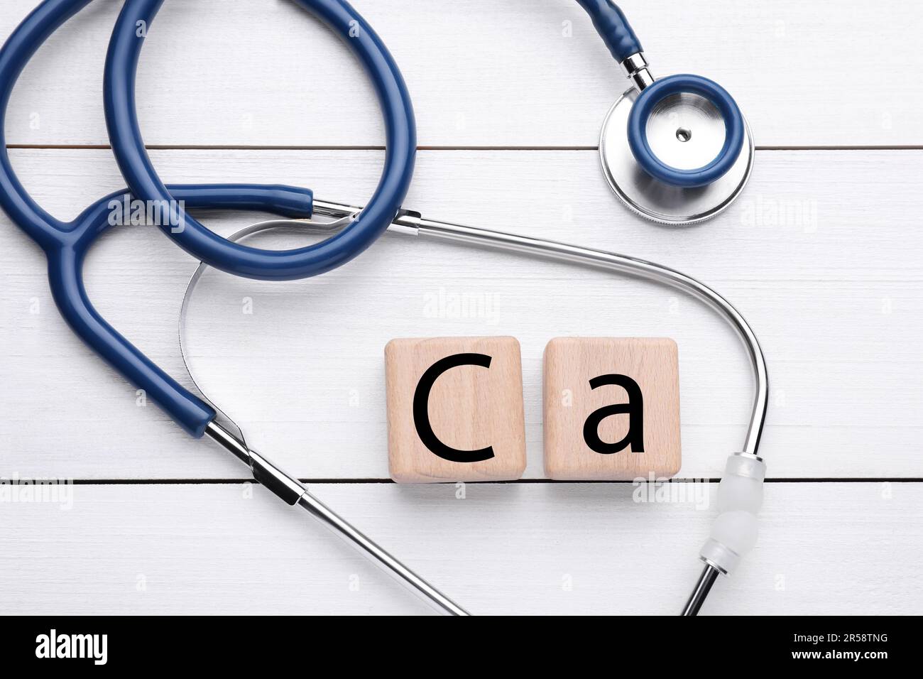 Cubes with symbol Ca (Calcium) and stethoscope on white wooden table ...