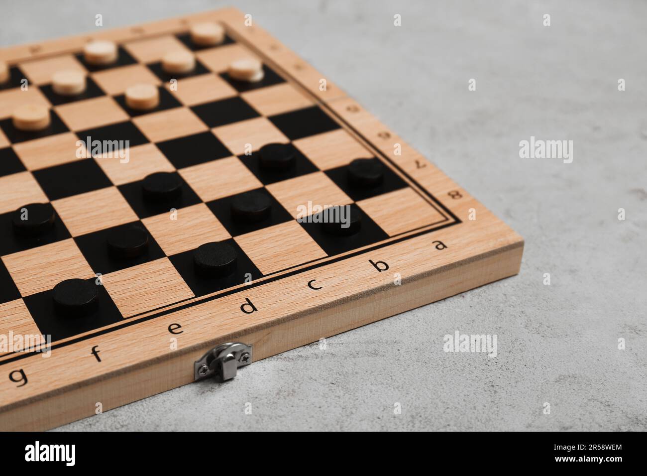 Wooden checkerboard with game pieces on light grey table, closeup Stock ...