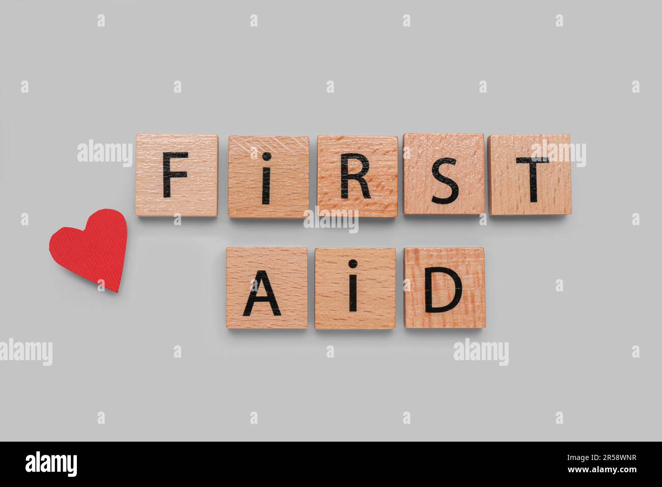 Words First Aid made of wooden cubes and cardboard heart on grey ...