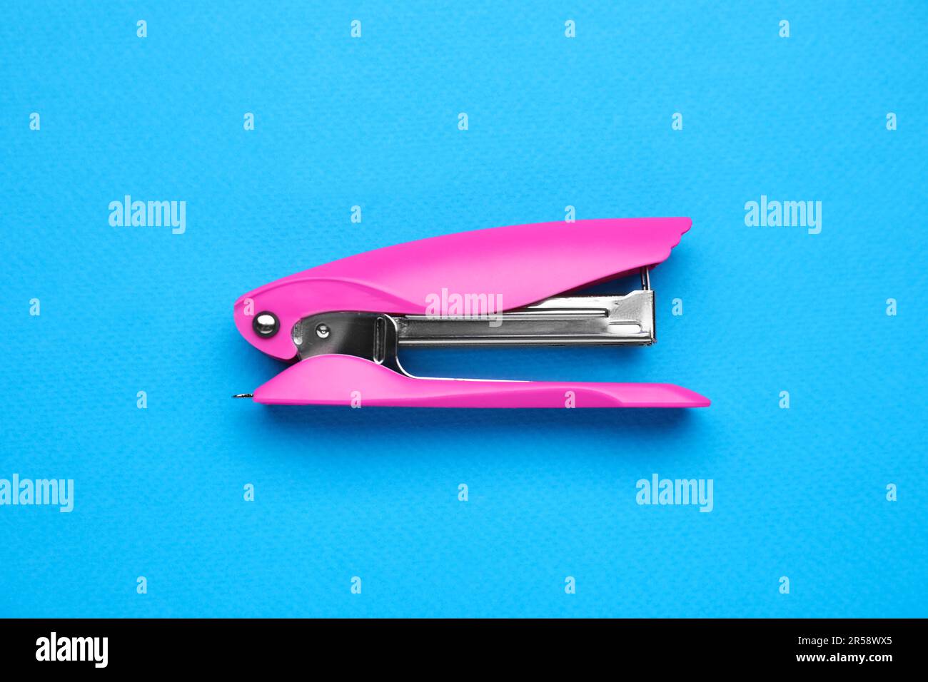 New bright stapler on light blue background, top view. School ...