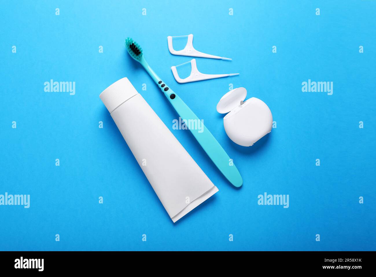 Container with dental floss, toothpaste and toothbrush on light blue ...