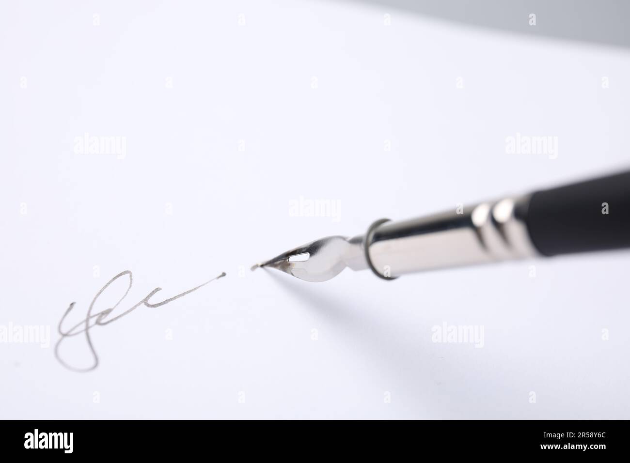 Signing on sheet of paper with fountain pen, closeup. Space for text ...