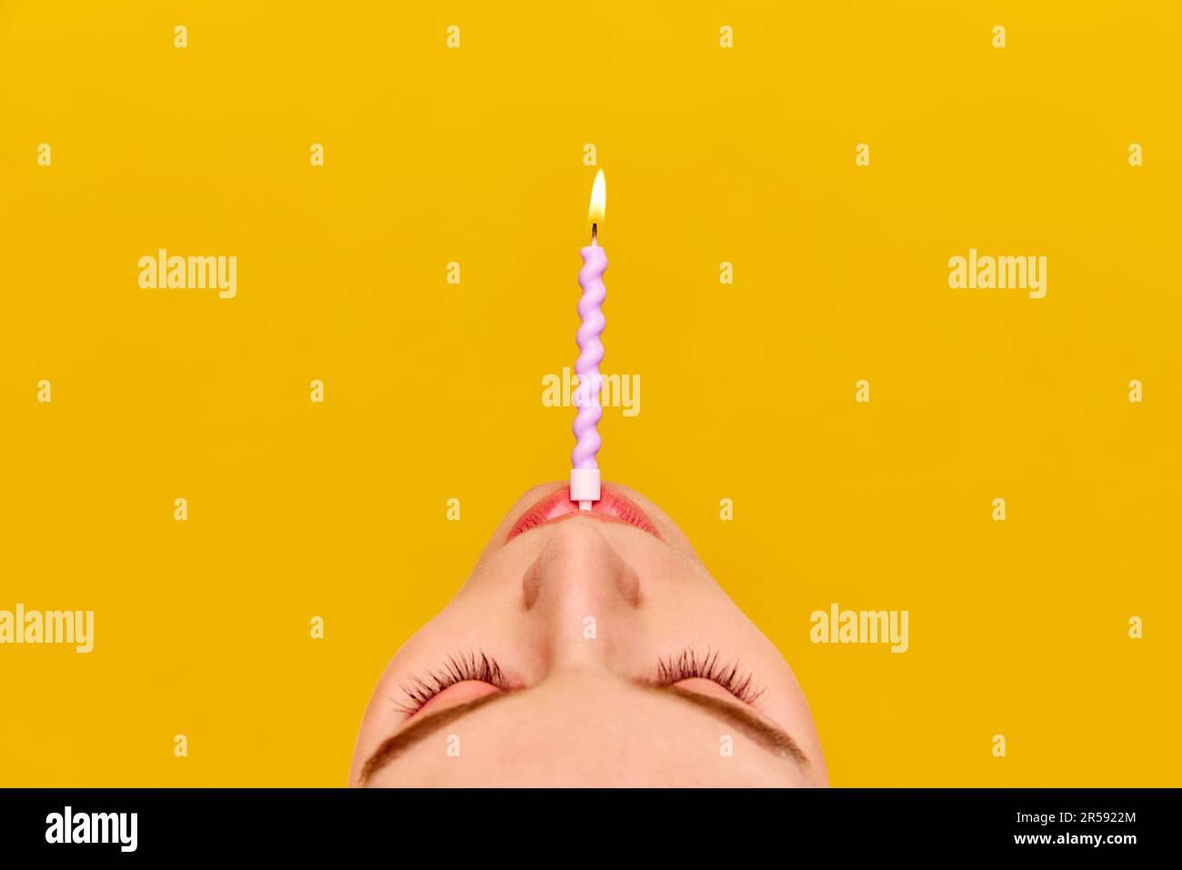 Cropped part of female face with burning candle against vivid yellow ...