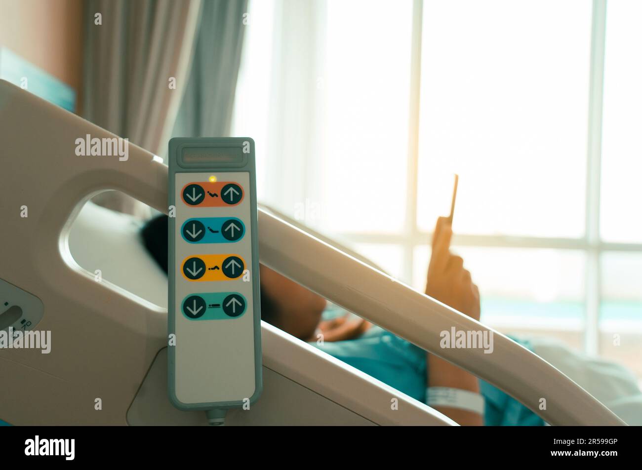 Hospital bed remote control hanging on the bed rail with woman patient ...