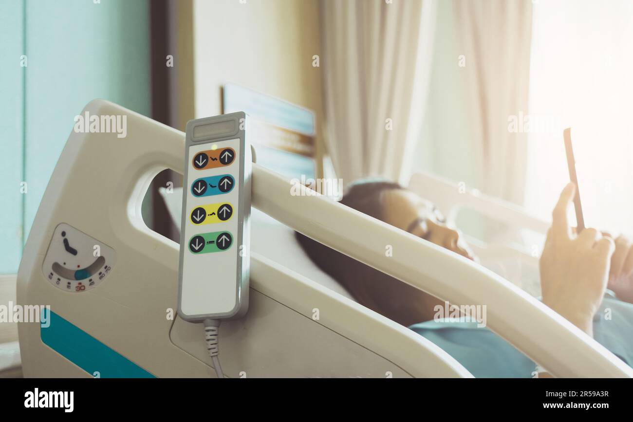 Hospital bed remote control hanging on the bed rail with woman patient ...