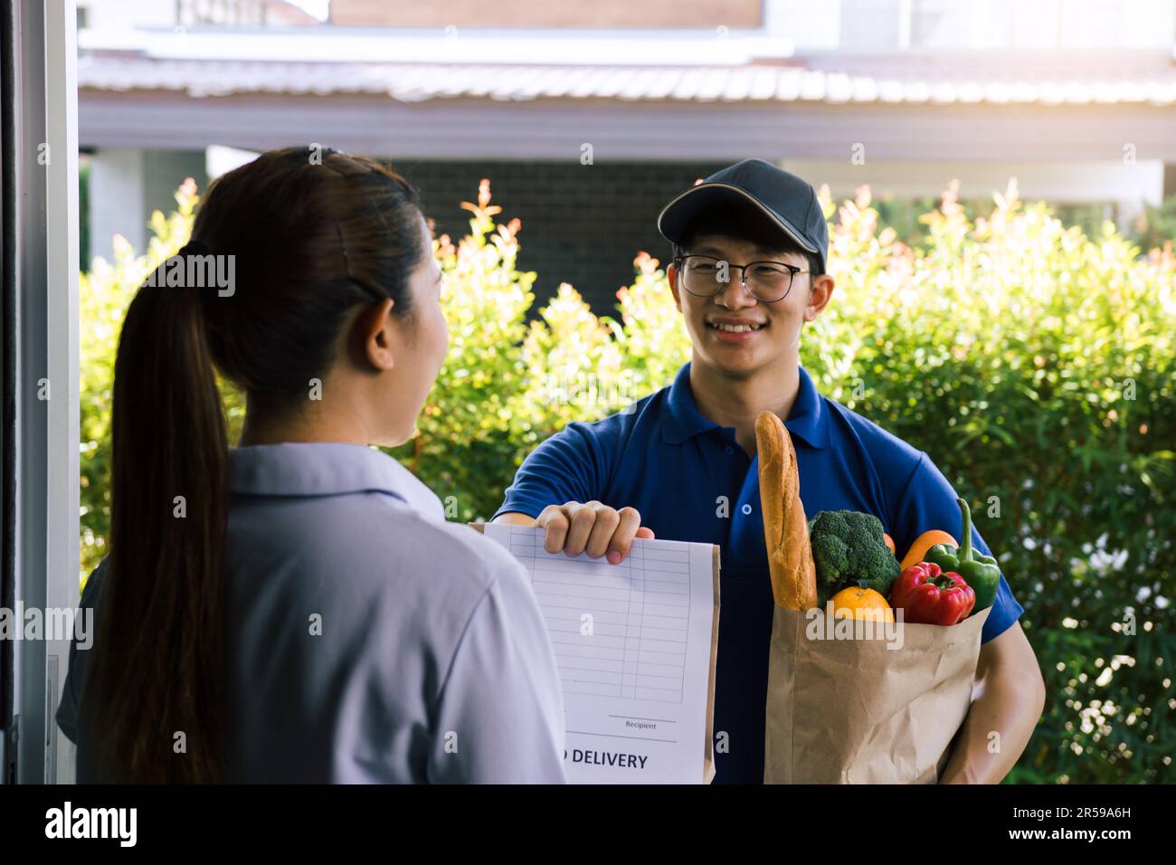 Supermarket food delivery staff deliver bags to female customers in ...