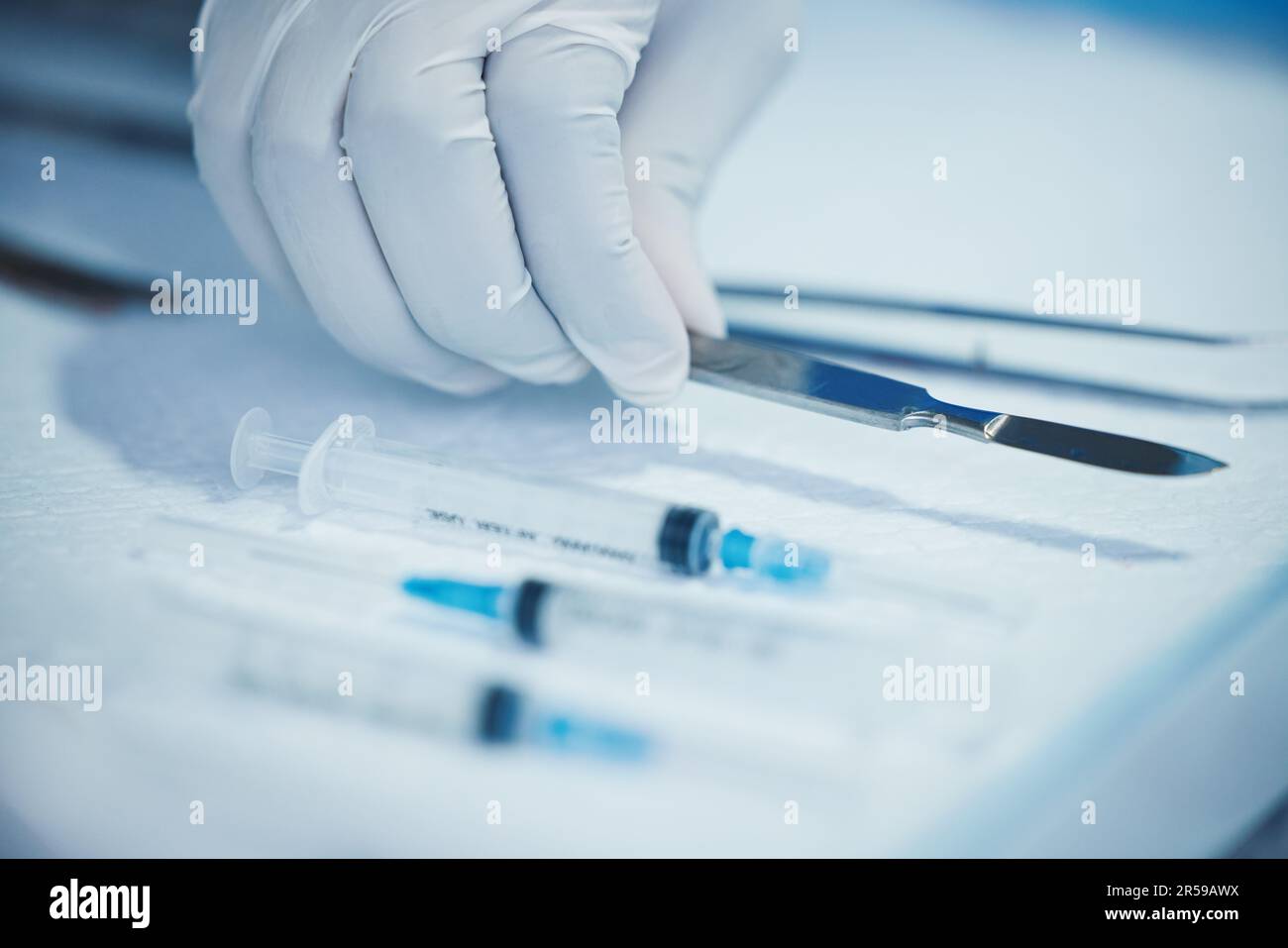 Closeup of hand, doctor and medical tools, scalpel and needle syringe ...