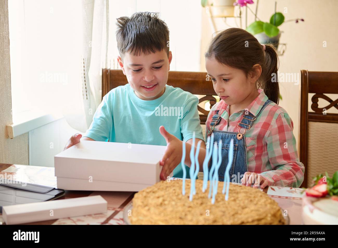 Authentic portrait of Caucasian adorable boy opening birthday present ...