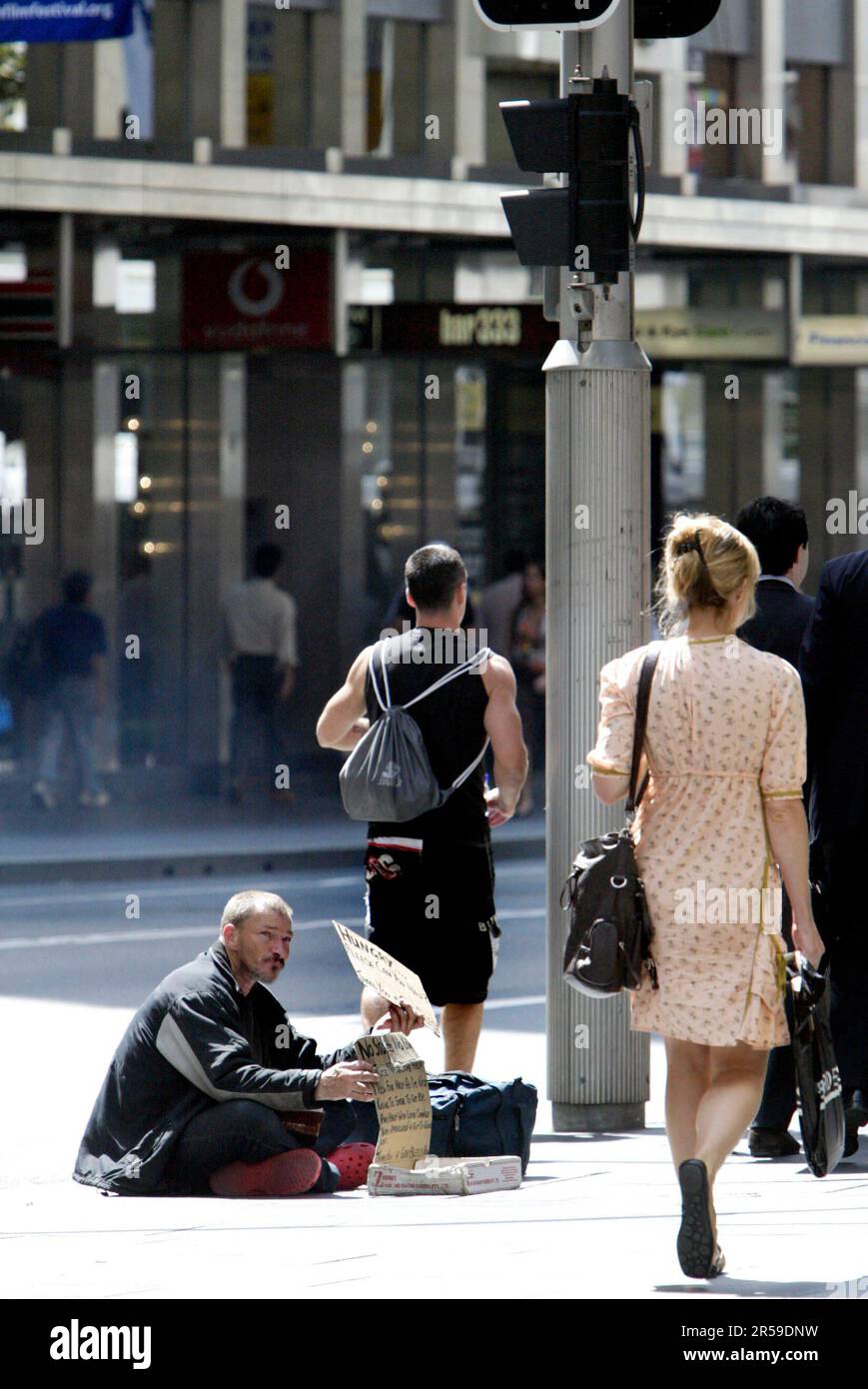 A homeless man begs with the aid of a placard on George Street at ...