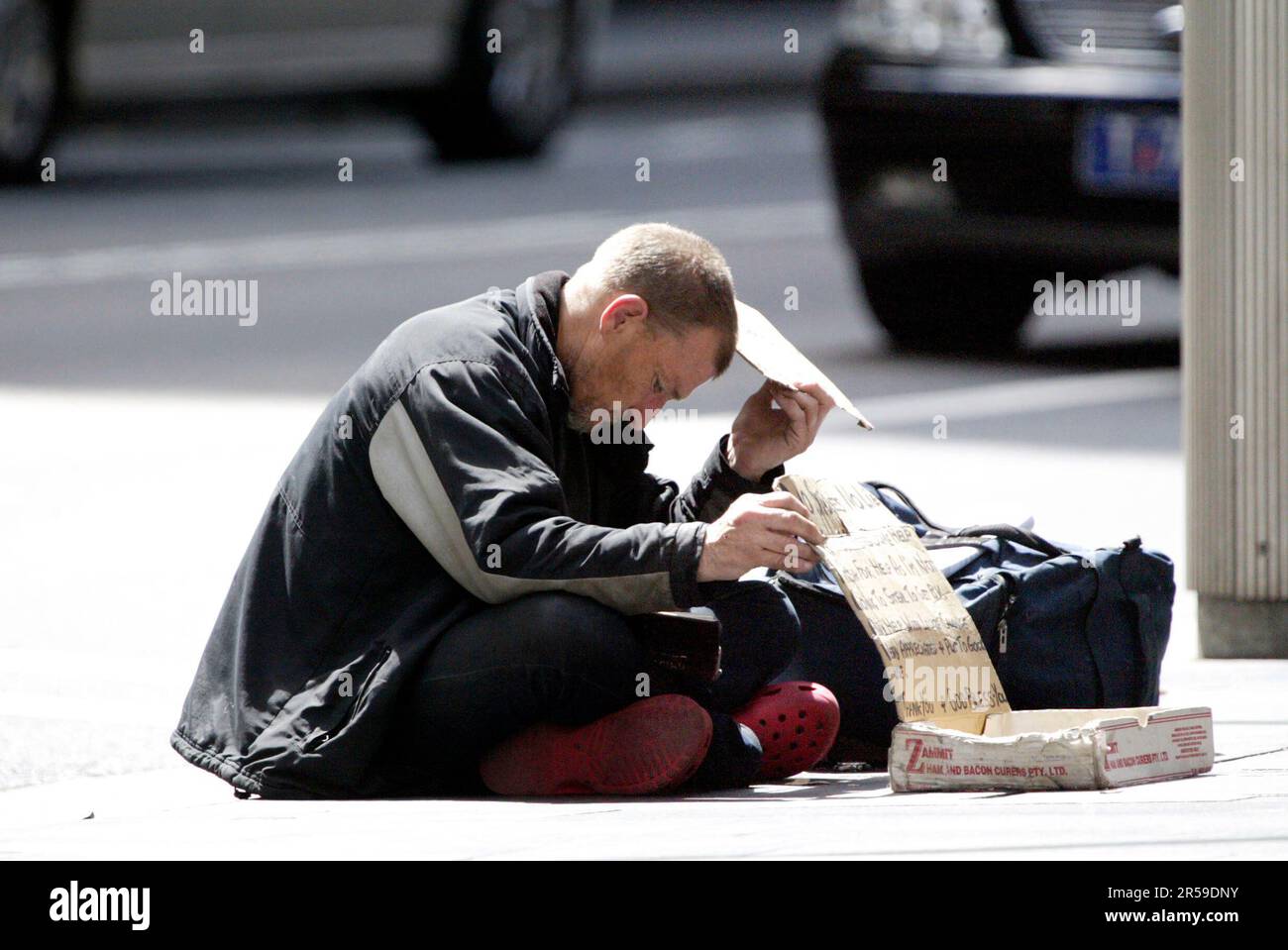 A homeless man begs with the aid of a placard on George Street at ...