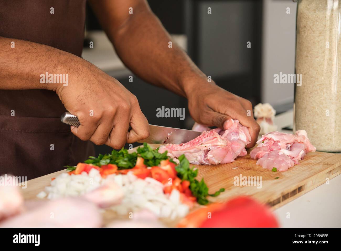 Unrecognizable young african man de-boning chicken to prepare a recipe ...
