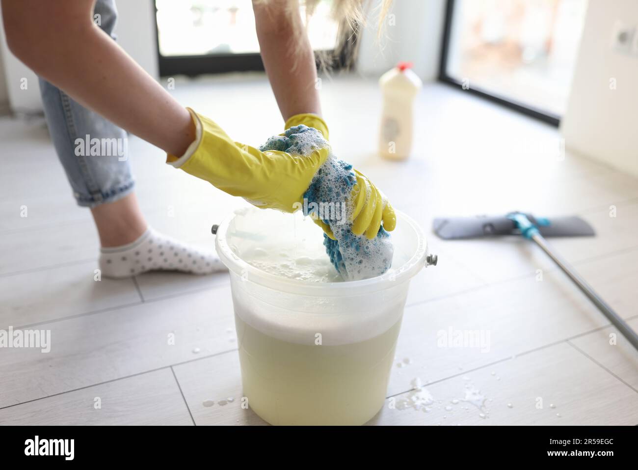 Woman in yellow gloves wrings mop rag over bucket in room Stock Photo ...