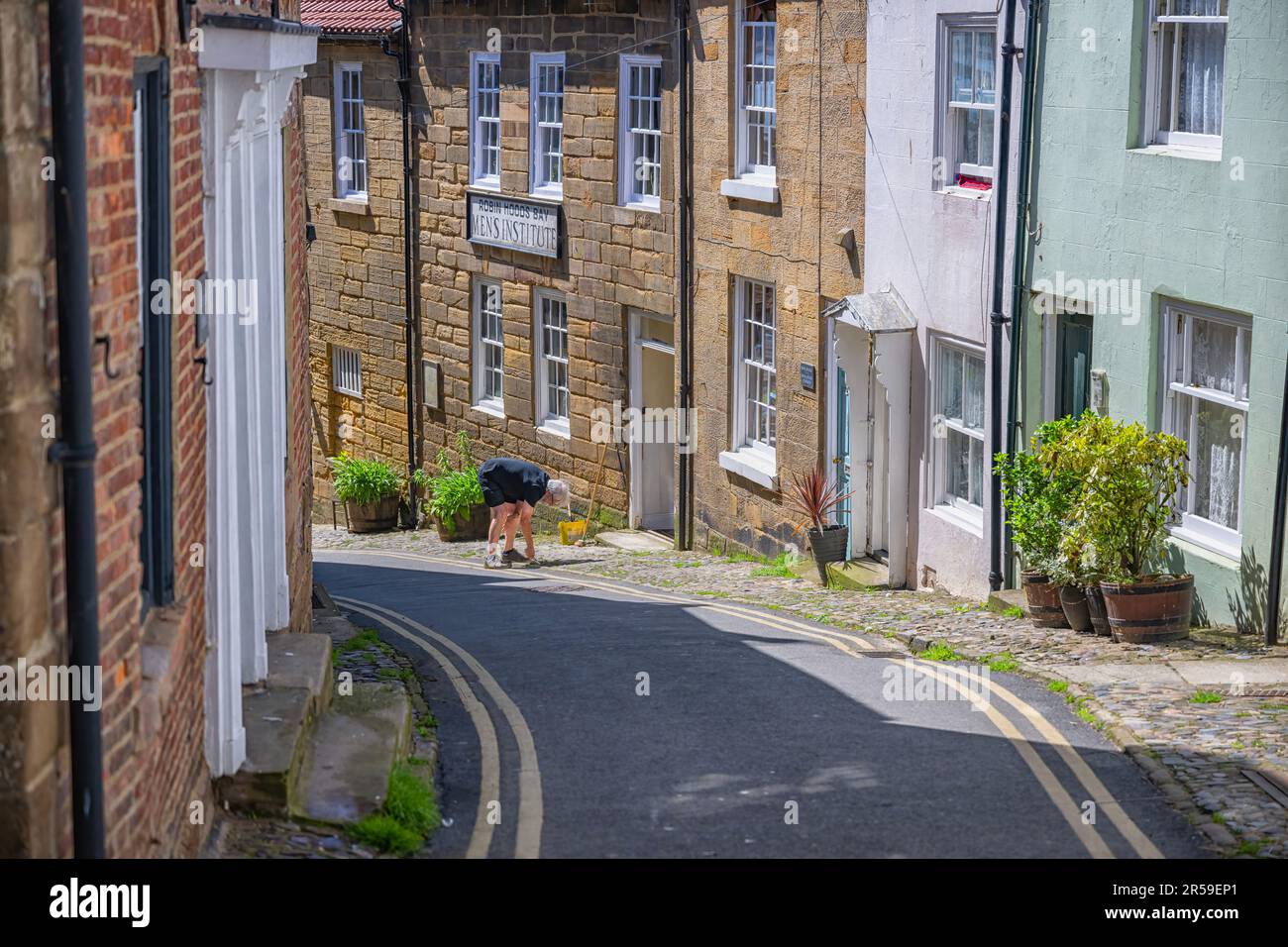 Narrow Street with man weeding the cobbles outside of his property at ...