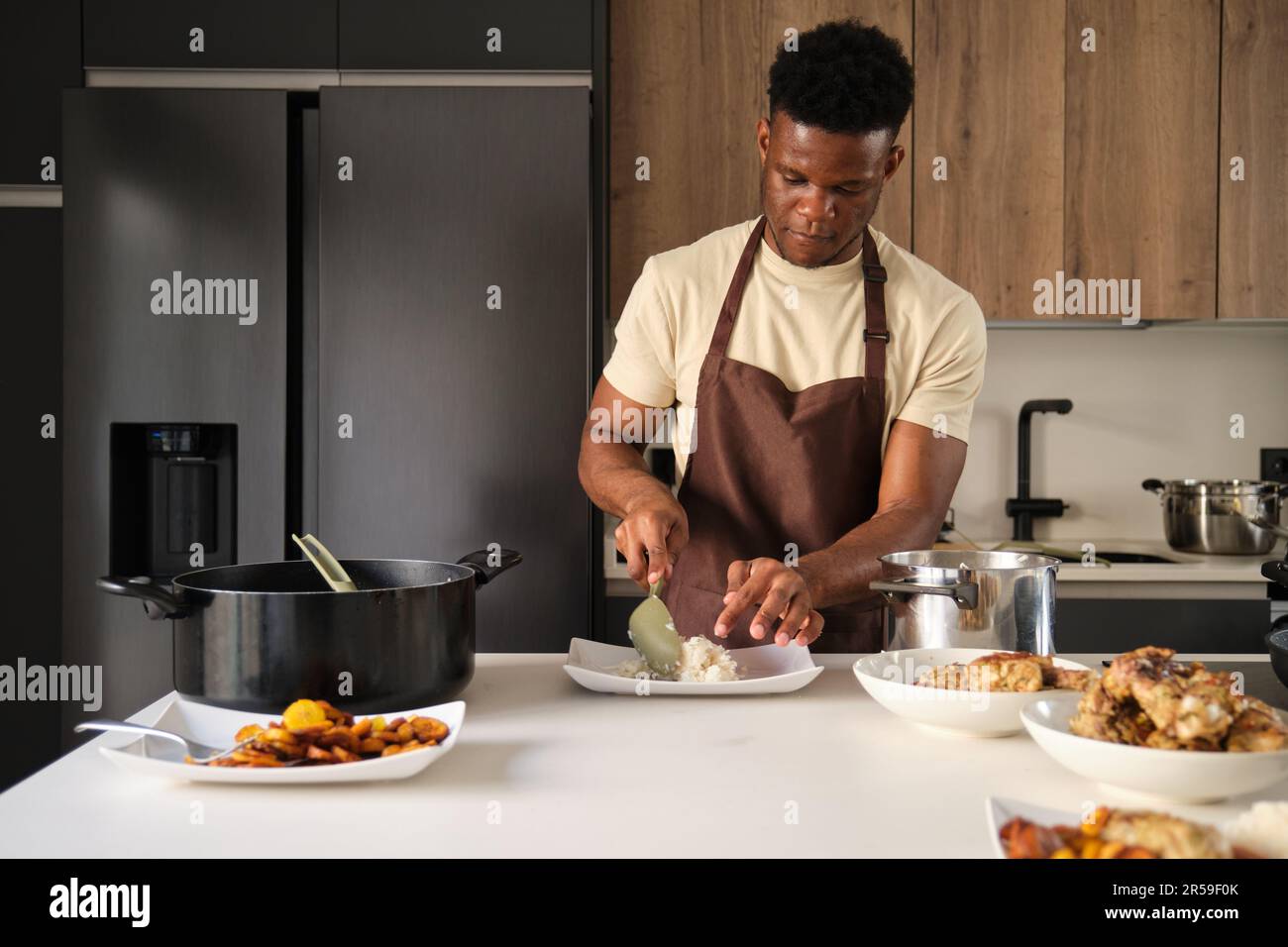 Young african man serving rice on a plate Stock Photo - Alamy
