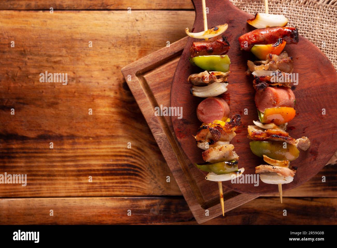 Homemade Skewers with meat and grilled vegetables served on a rustic wooden board, also known as ...