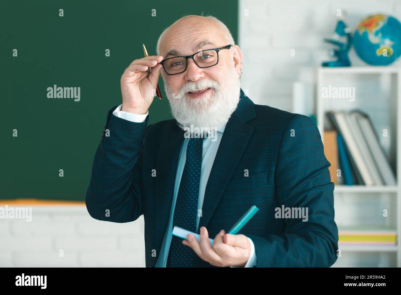 Elderly professor, teacher on a blank chalkboard during lesson. Senior ...