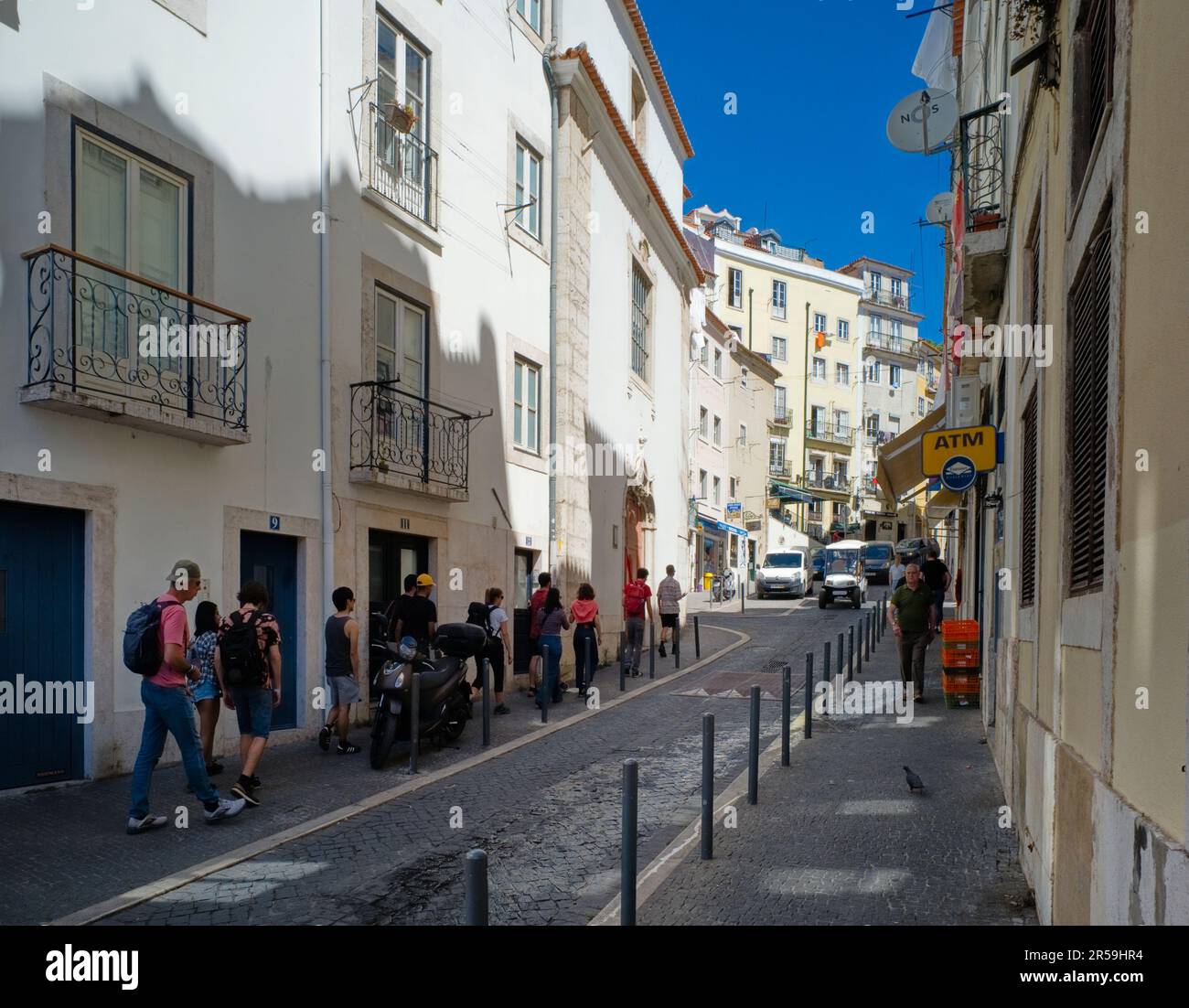 A crocodile of tourists following a guide in the Alfama district of ...